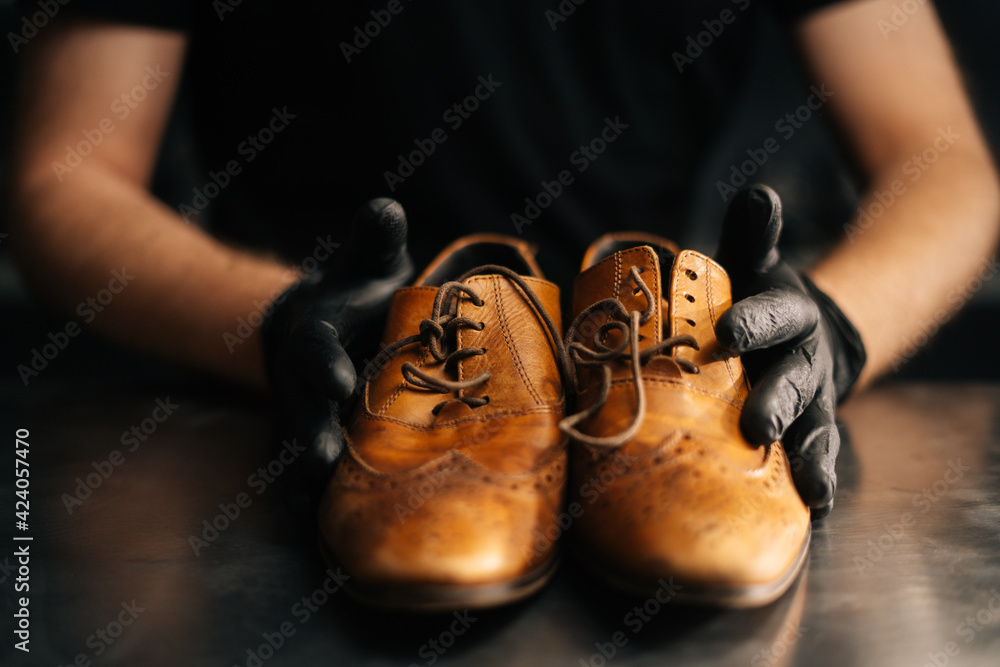 Close-up front view of hands of shoemaker shoemaker in black gloves ...