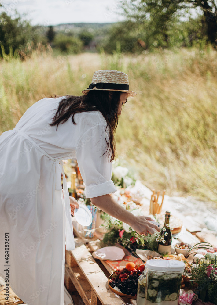 the woman takes food from the table. a girl in a white dress bent over ...
