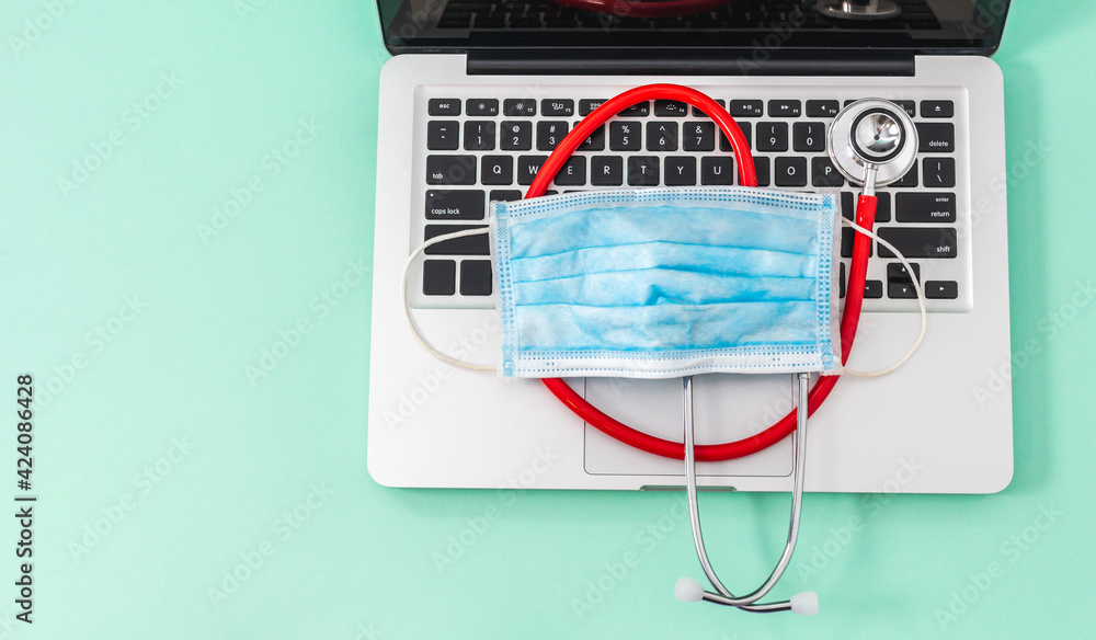 Surgical mask over a stethoscope placed above a computer keyboard on a ...