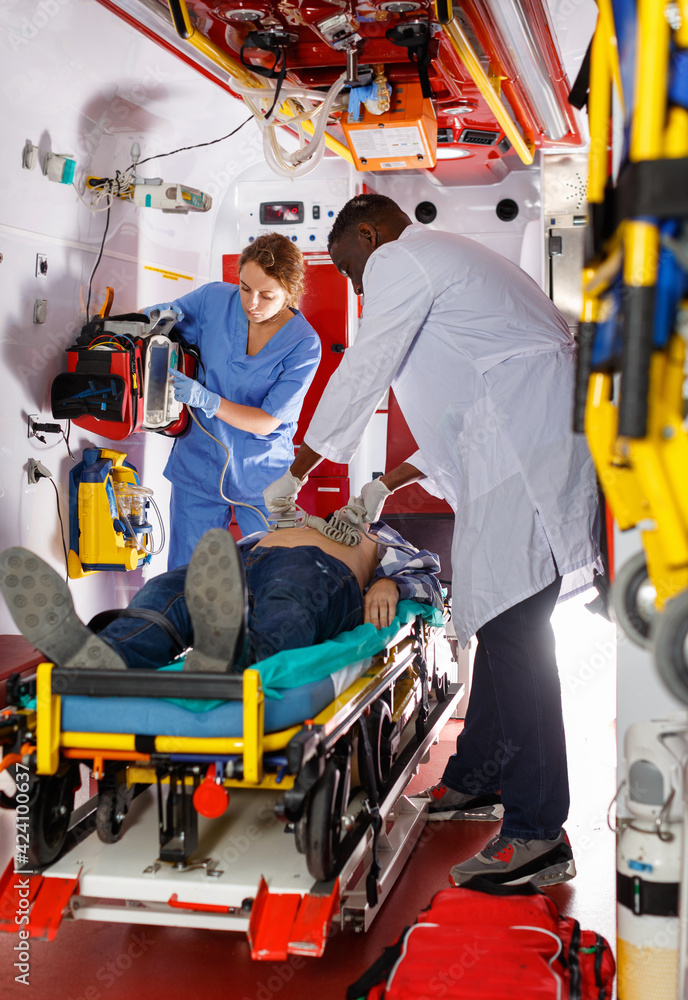 Serious emergency doctor resuscitating male patient with help of ...