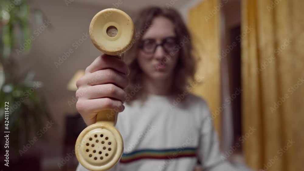 Close-up of yellow vintage telephone handset in male hand with blurred ...