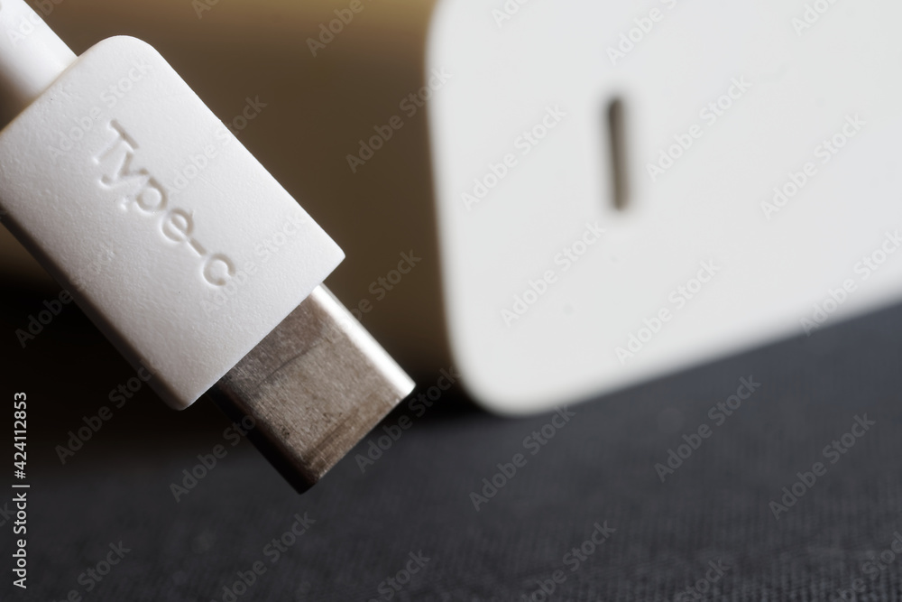 One white usb type-c connector on a dark background next to a white ...