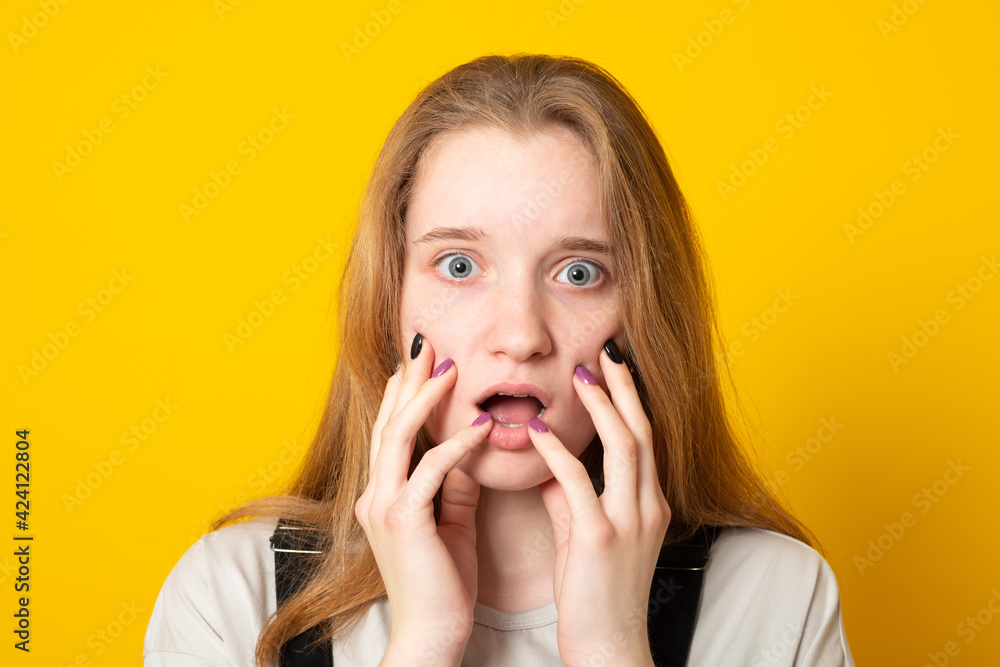 Nervous scared girl grabs face and looks with worried expression at ...