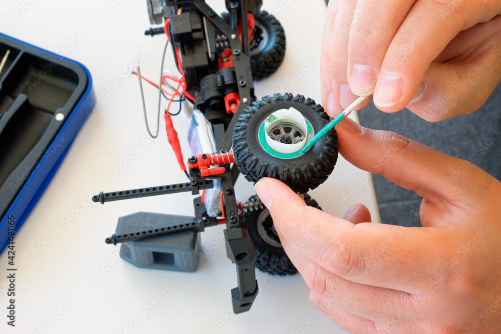 Close up on a male hands while painting rims of a scale model machine ...