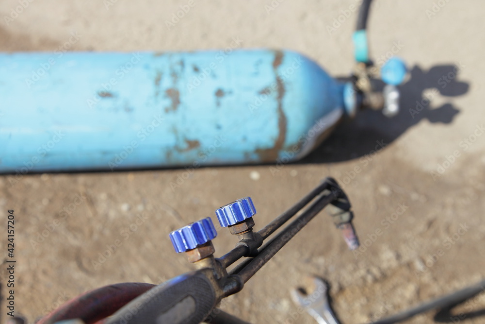 Oxygen-propane gas burner torch closeup on blue oxygen cylinder ...