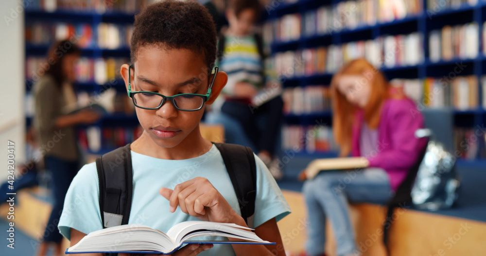 Smart african-american student boy reading book in library Stock Photo ...