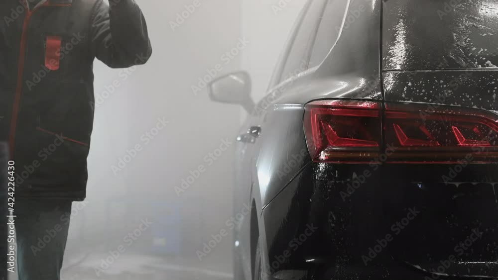 Make worker washing black car arches under high pressure water after ...