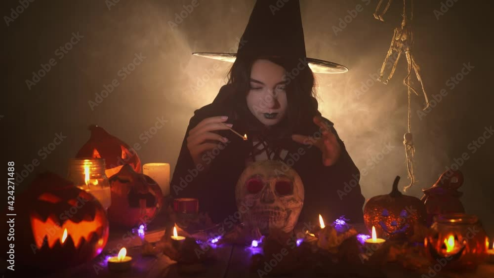 Woman in the image of witch is conjuring over the skull with a joss ...