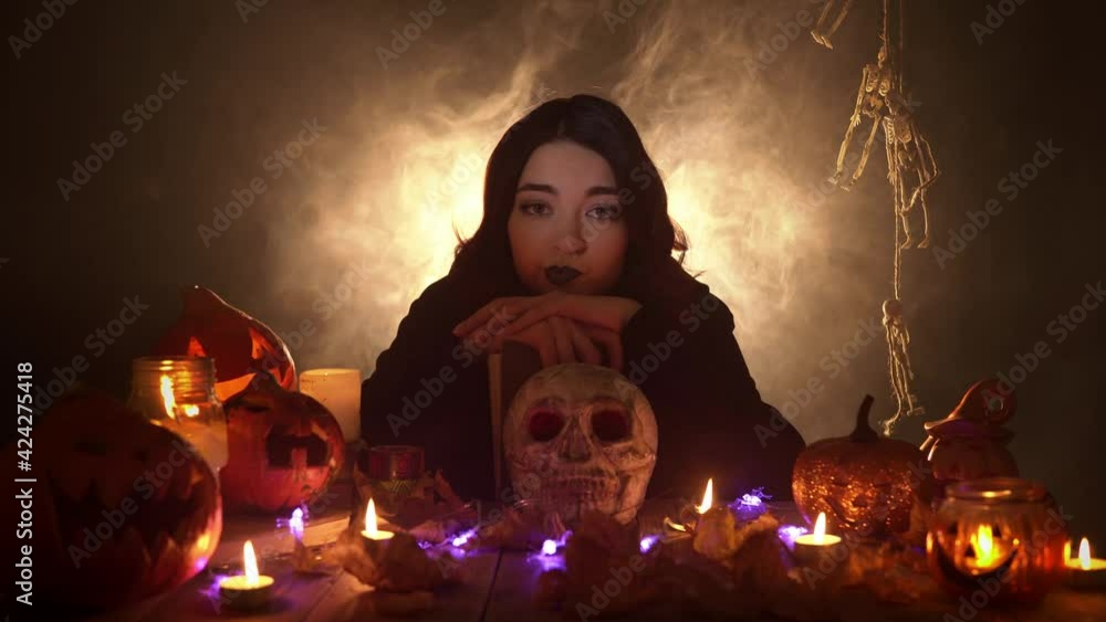 A bored young woman in the image of witch is sitting leaning on the ...