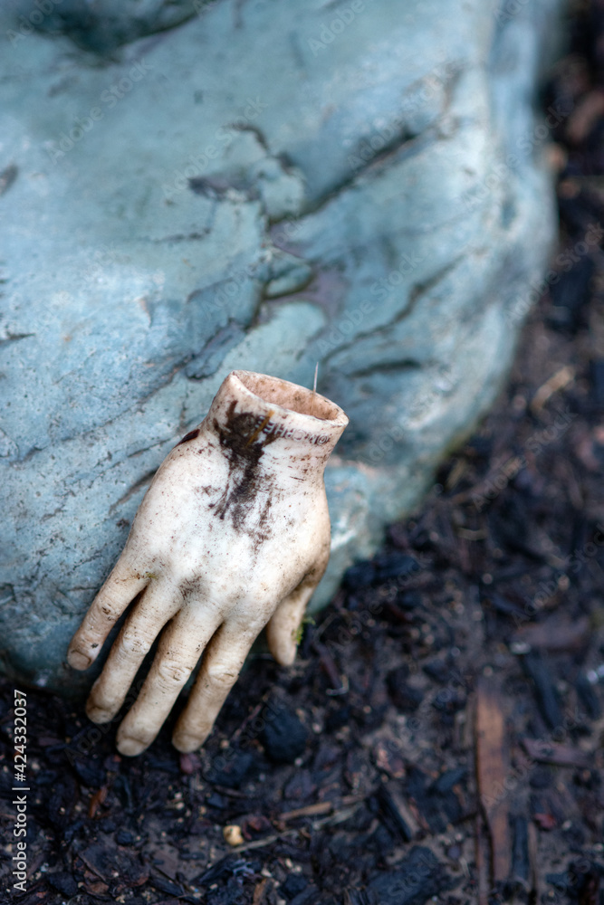 Creepy, realistic doll hand, scratched, moldy and dirty on a blue-toned ...