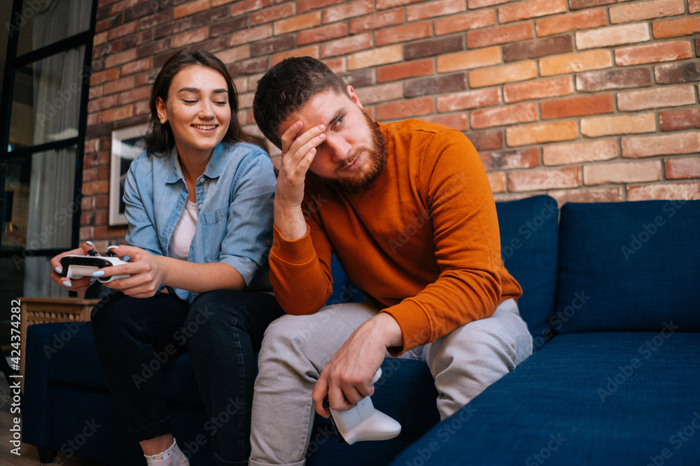 Young couple playing video games on console sitting together on couch ...