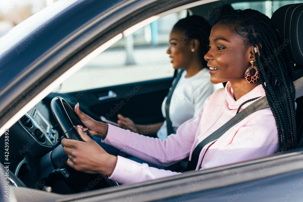Two african young women on car trip driving the car and making fun ...