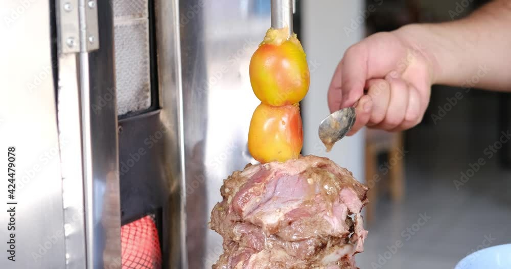 Close up of hands adding fats and oil on kebab meat while cooking on ...