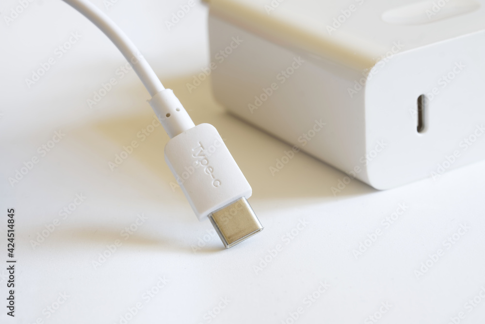 A white usb type-c connector with a wire lies on a light background ...