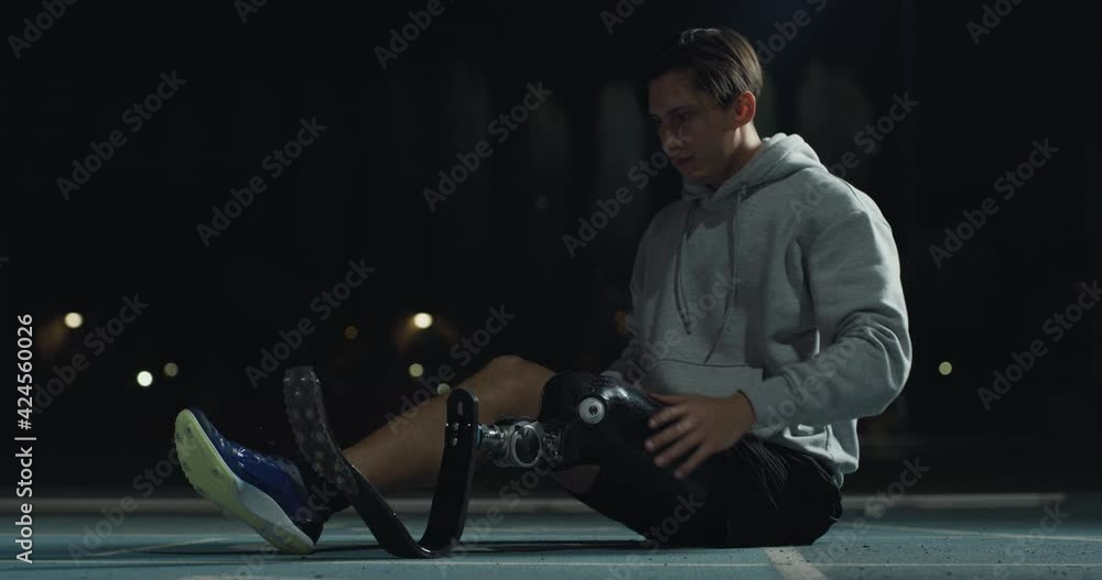 Cinematic shot of disable man with legs prosthesis is warming up before ...