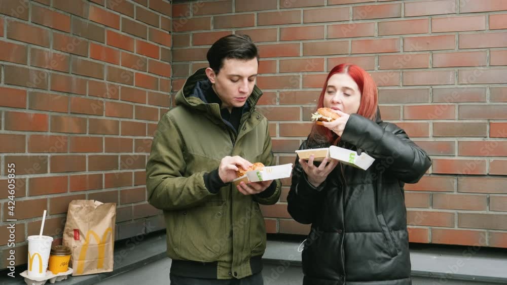 Young people couple date stand eating fast food burger outdoors near ...