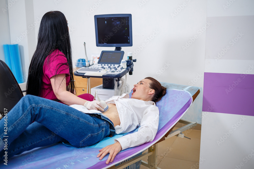 A young woman lies on a couch, a doctor appointment, an ultrasound scan ...