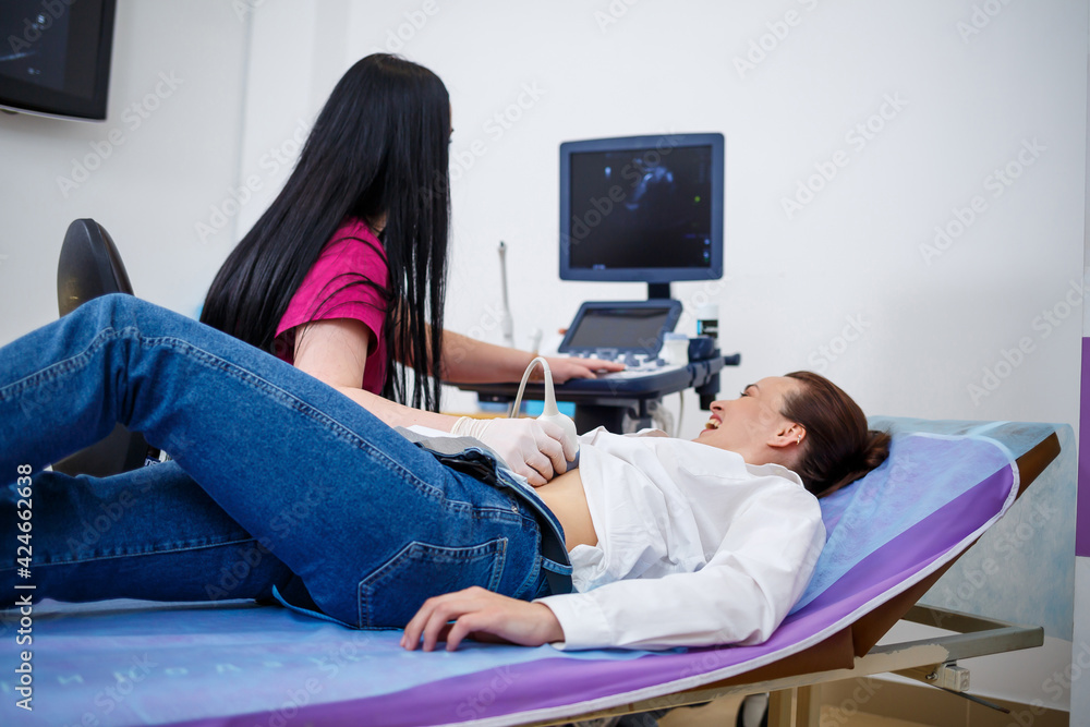 A young woman lies on a couch, a doctor appointment, an ultrasound scan ...