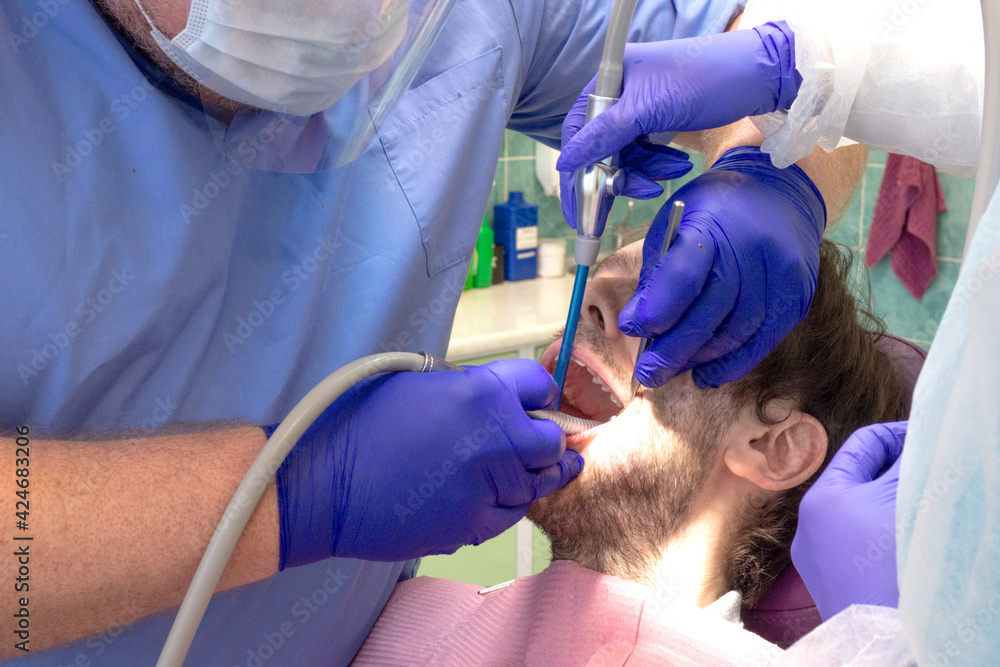 Foto de Team of dental surgeons performs surgery on teeth. in a modern ...