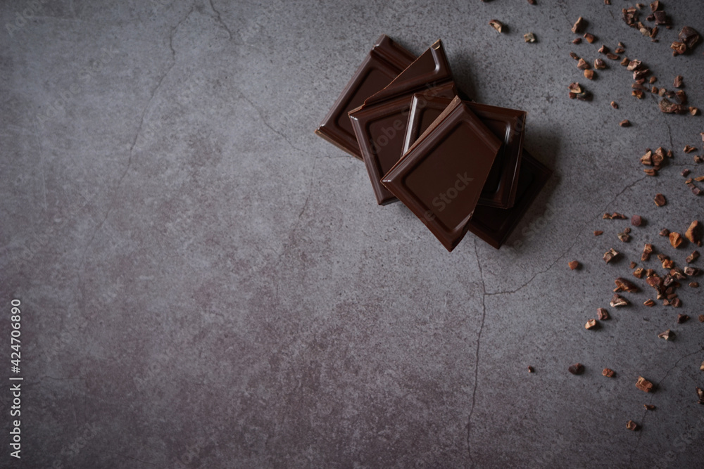 Pieces of dark chocolate with raw cacao nibs on dark stone background ...