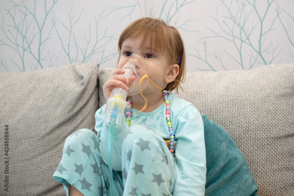Kid girl makes inhalation with a nebulizer. sick child holding ...