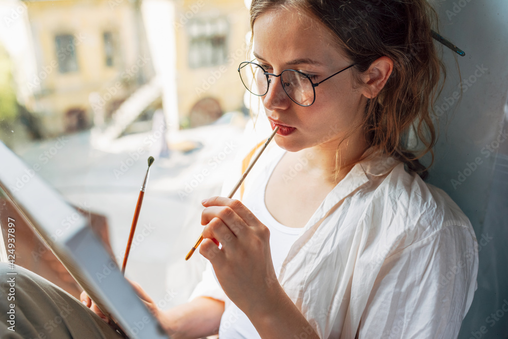 Closeup of a Cacucasian female artist painting on canvas in her art ...