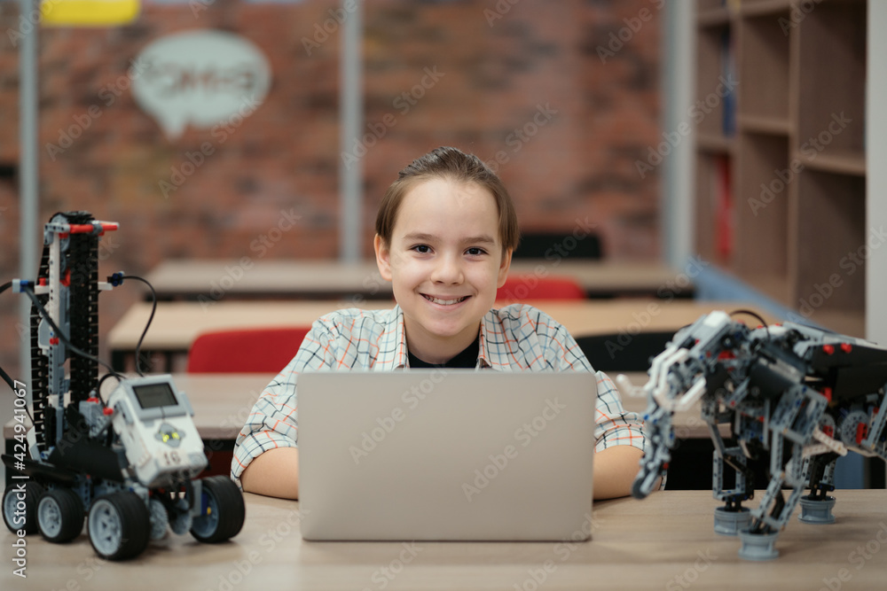 Boy using a laptop to program assembled robot from plastic bricks. STEM ...