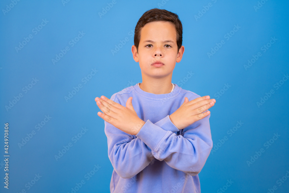 Cute Caucasian kid boy wearing casual sweater against blue wall. Angry ...