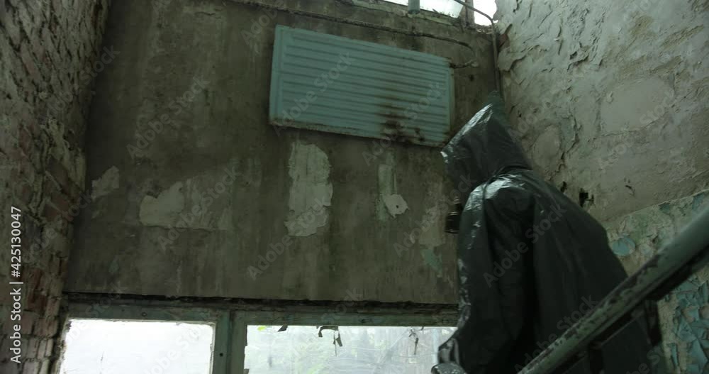 a man in overalls and a gas mask with a canister in his hand goes down ...