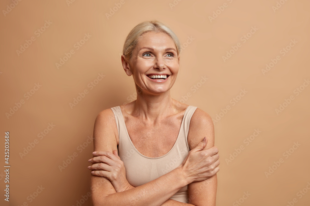 Attractive positive wrinkled fifty years old woman looks gladfully ...