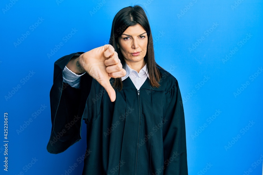 Young hispanic woman wearing judge uniform looking unhappy and angry ...