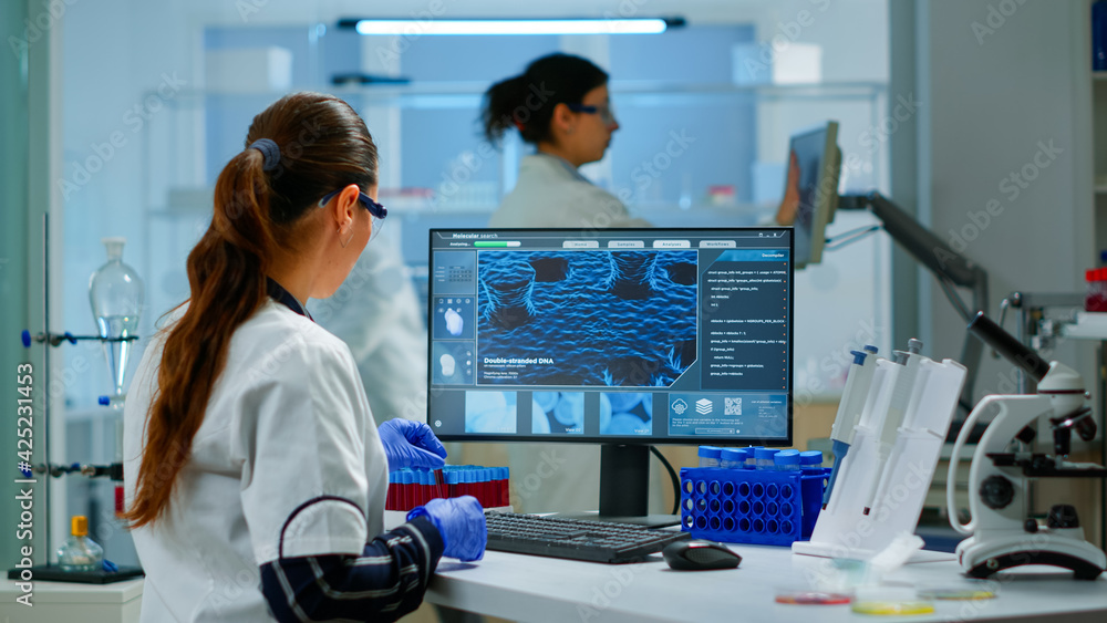 Laboratory doctor holding at blood sample and writing on computer while ...