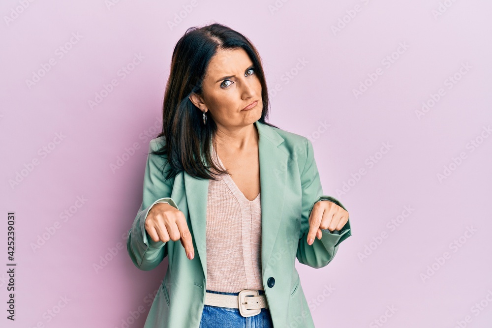 Middle age brunette woman wearing casual clothes pointing down looking ...