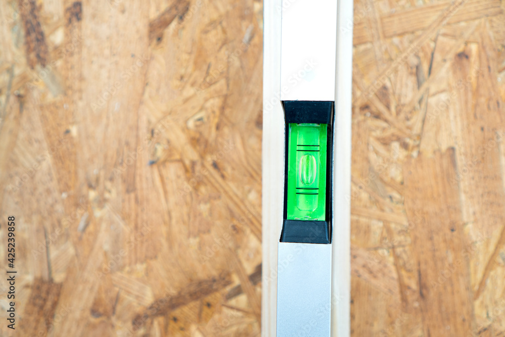 Water level tool lying on the OSB sheet. Spirit level bubble shows the ...