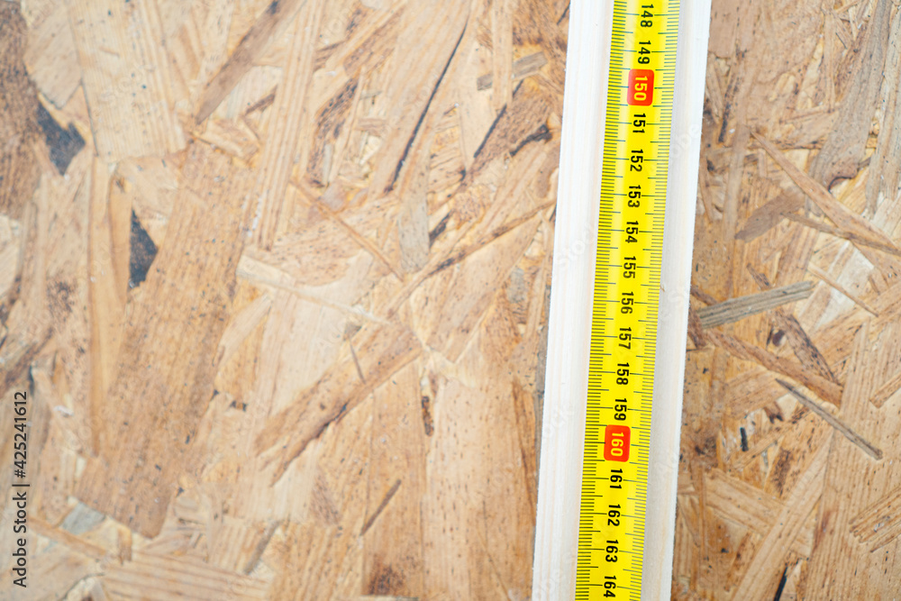 Building measure tape and wooden log lying on the OSB sheet ...