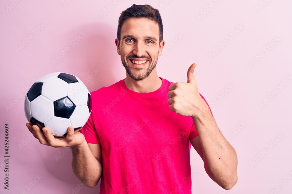 Young handsome player man playing soccer holding football ball over ...