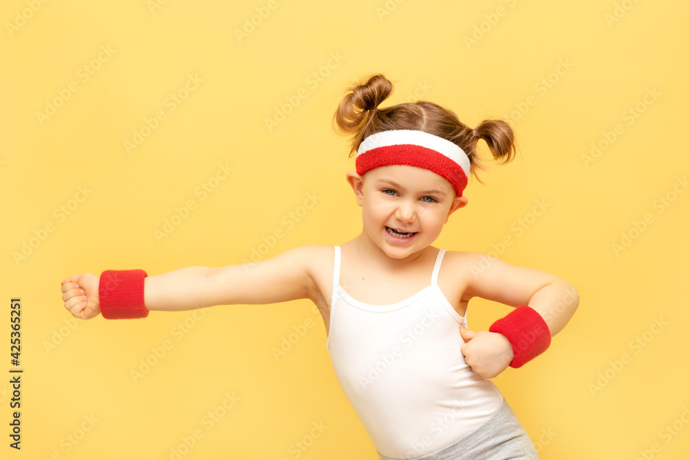 Smiling fitness child in sportswear over yellow studio background ...