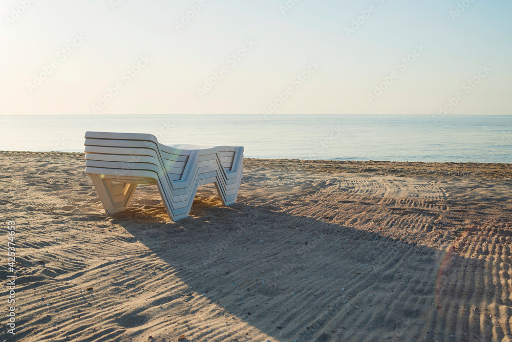 Folded plastic deck chairs on a deserted beach by the sea. The failure ...