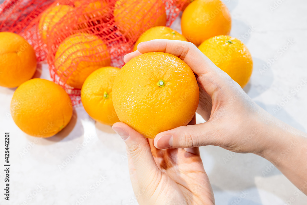 Fresh quality selection orange in two hand with red net bag as blurred ...