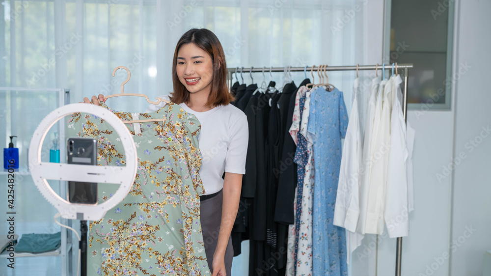 Beautiful woman Influencer showing clothes in front of smartphone to ...