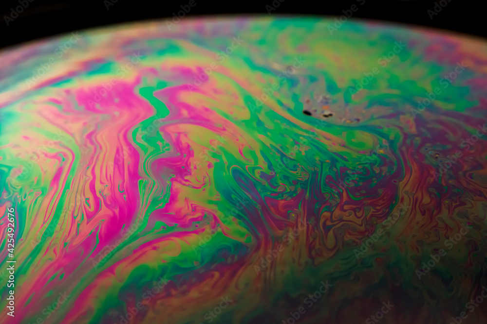 The colorful close-up surface of a soap bubble with weird psychedelic ...