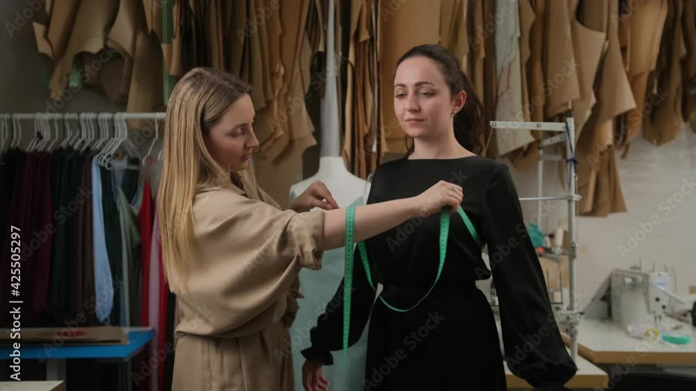 Femail seamstress taking measurements of female client using tape in ...