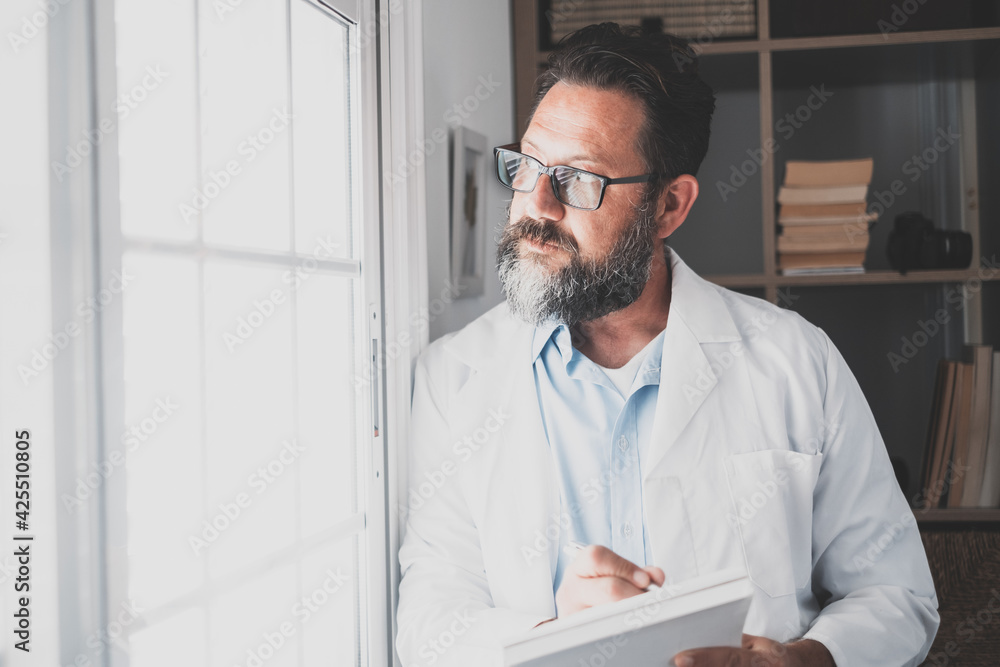 Pensive young male caucasian doctor in white medical uniform look in ...