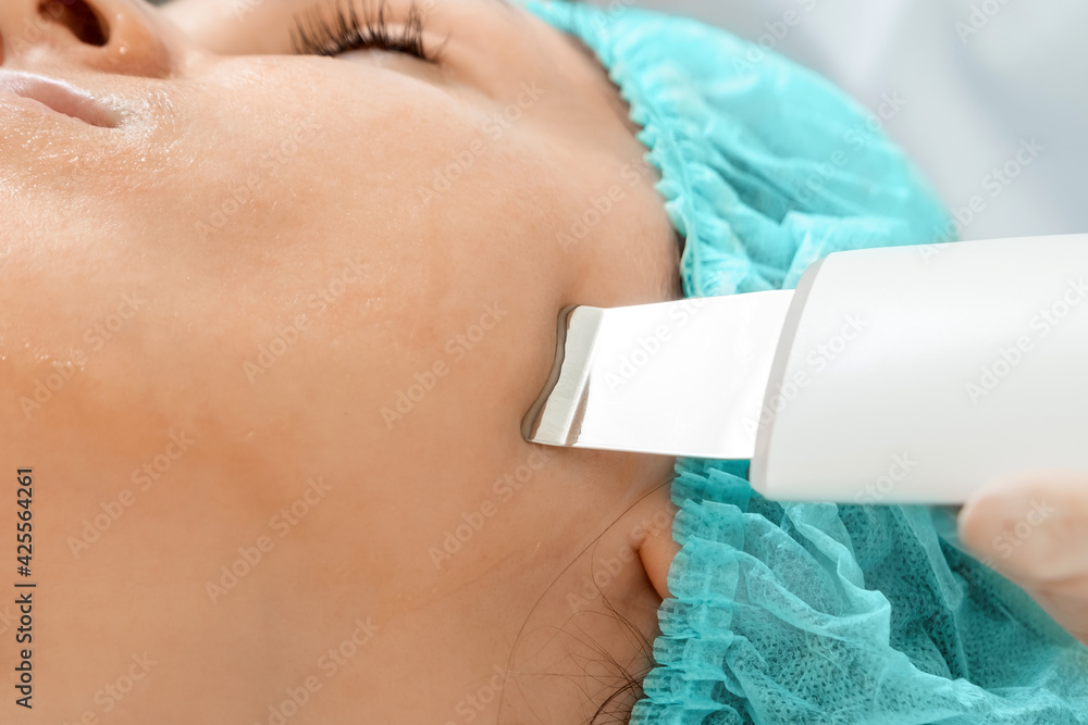 A gloved beautician cleanses the skin on the face using a special gel ...