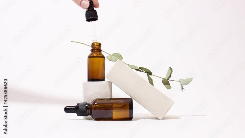 Hand is opening brown dropper glass bottle and pouring out serum of ...