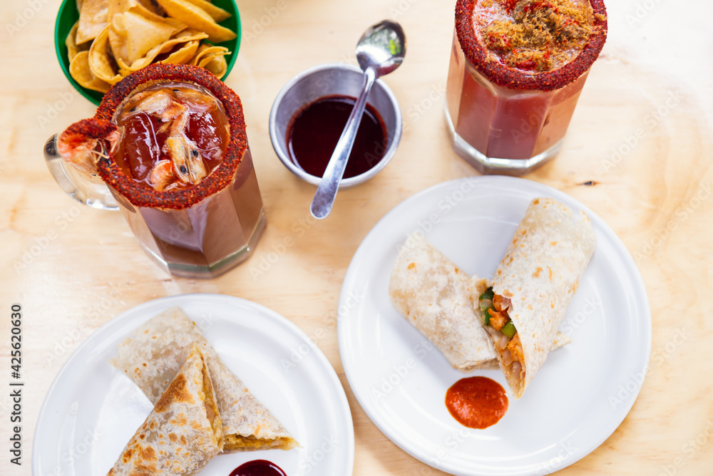Foto de Mexican burrito and michelada beer with tomato juice with copy ...