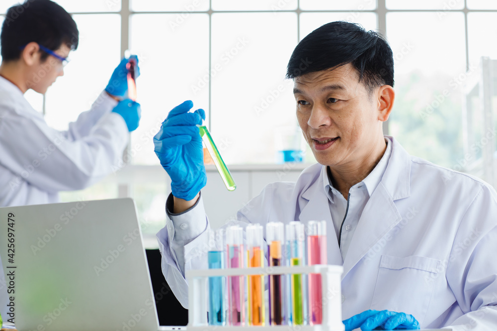 2 asian men are scientist holding and look at test tube with chemical ...