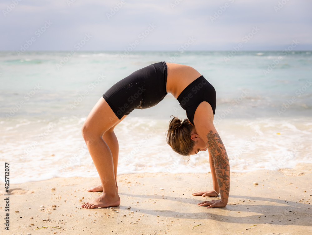 Beach yoga. Young woman practicing Chakrasana or Urdhva Dhanurasana ...