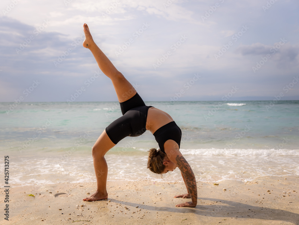 Outdoor yoga. Young woman practicing Eka Pada Chakrasana, One Legged ...