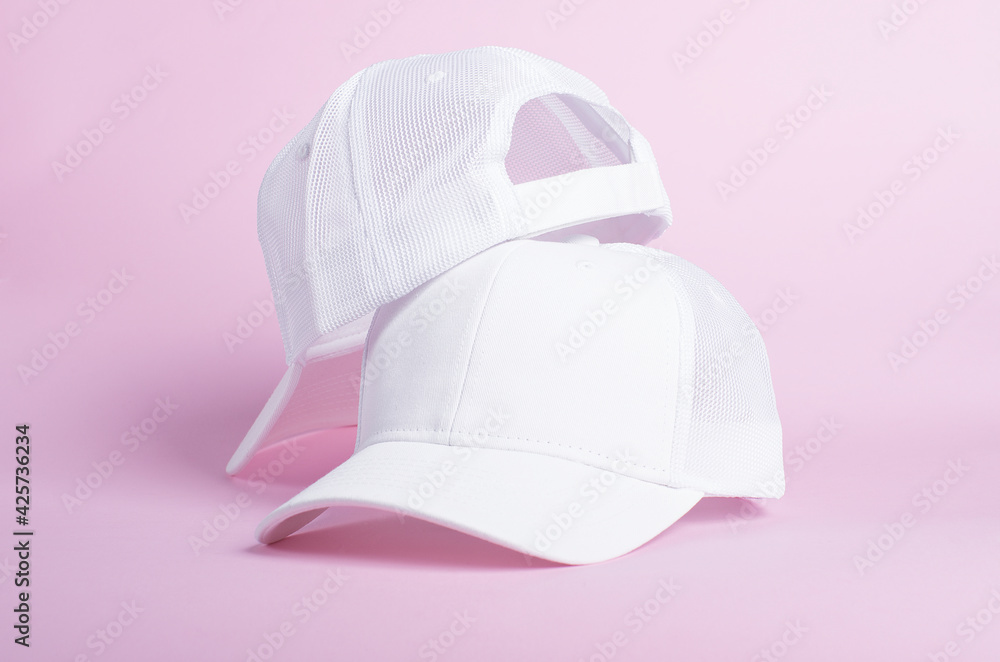 Two white baseball caps isolated on a pink background, front and back ...